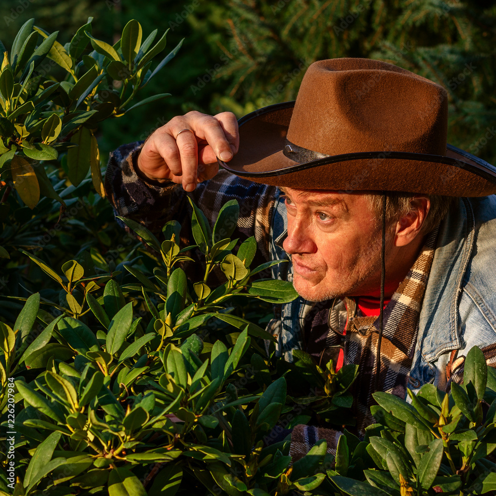 Foto de Senior adult man or a farmer, in a brown cowboy hat, looks out ...