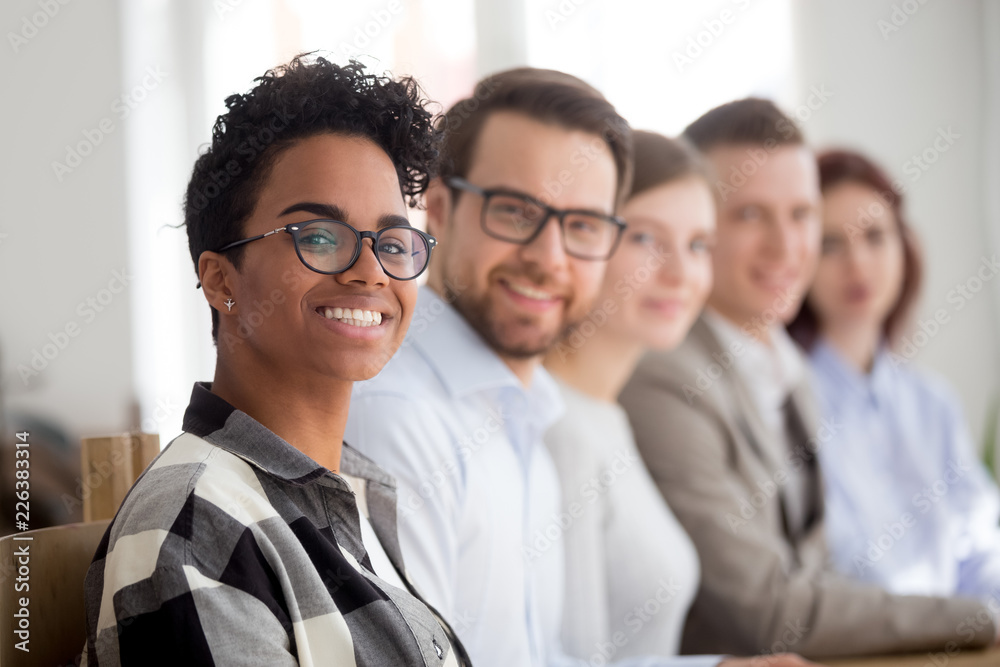 Five happy confident successful multiracial team smiling sitting ...