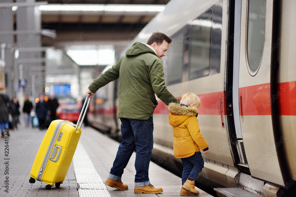 Little boy and his father go in express train on railway station ...