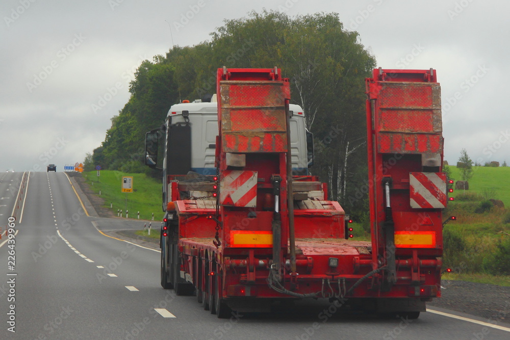 Heavy truck with red low-frame four-axle semi-trailer trawl on a two ...