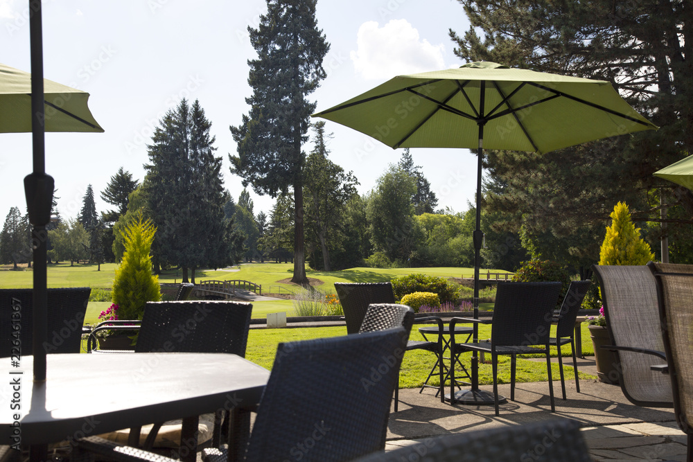 Sunlit patio with table, chairs and umbrella with view of golf course ...