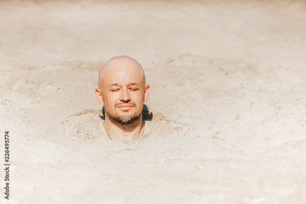Male bald head above sand. Man buried alive in desert. Punished boy ...