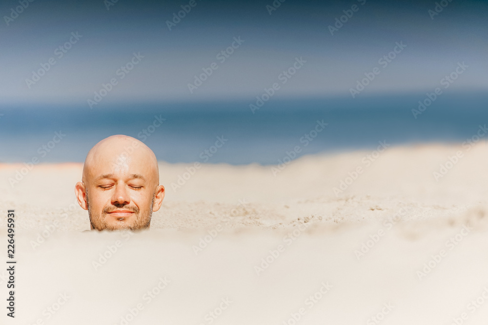 Male bald head above sand. Man buried alive in desert. Happy person ...