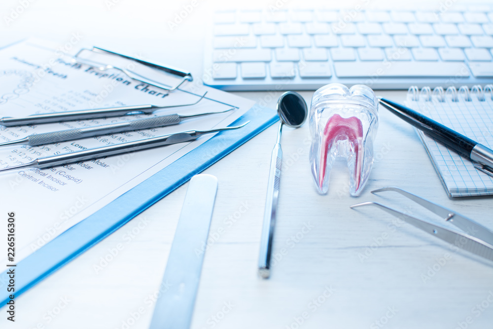 Dentist tools, tooth eruption chart and tooth model on table with ...