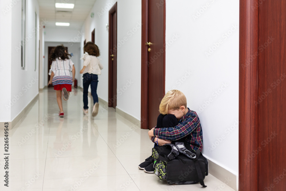 Crying little boy suffering an act of bullying at school from two ...