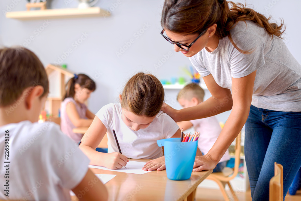 Preschool teacher assisting children with their drawings. Early education. Harnessing creativity ...