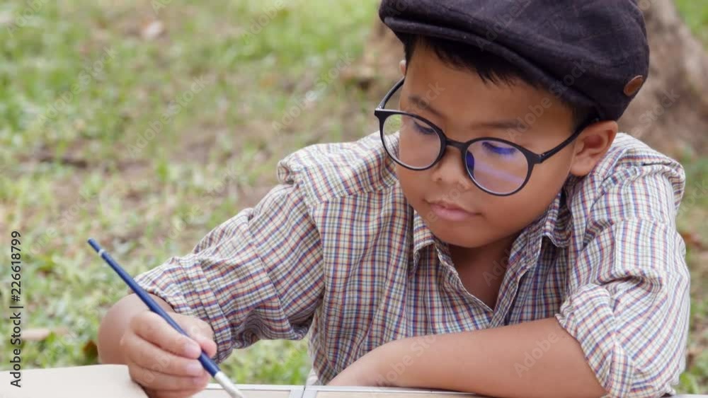 Boy drawing picture in book at nature background. People with education ...