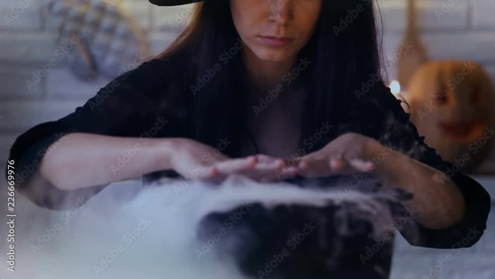 Scary witch making magic potions in her pot with white smoke, Halloween ...