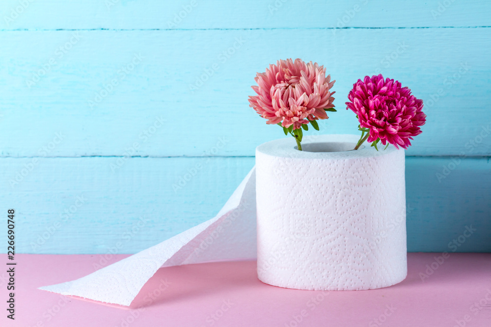 Scented toilet paper roll and flowers on a blue background on a pink ...