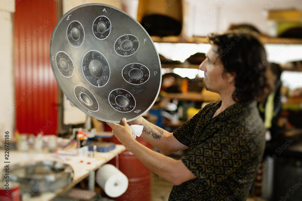 Artisan in his workshop holding the finished design of a handpan, a ...