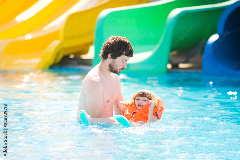 Happy family having fun together in outdoors swimming pool in water ...