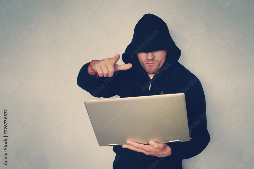 Hacker holding gun working on his computer terrorist and bandit concept ...