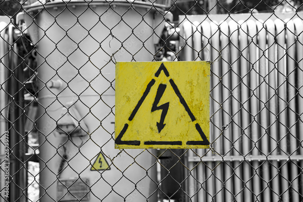 warning sign of electricity, high voltage, hanging on the fence around ...