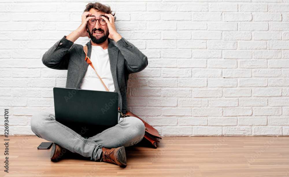young man sitting on the floor with a crazy, amazed look of surprise ...