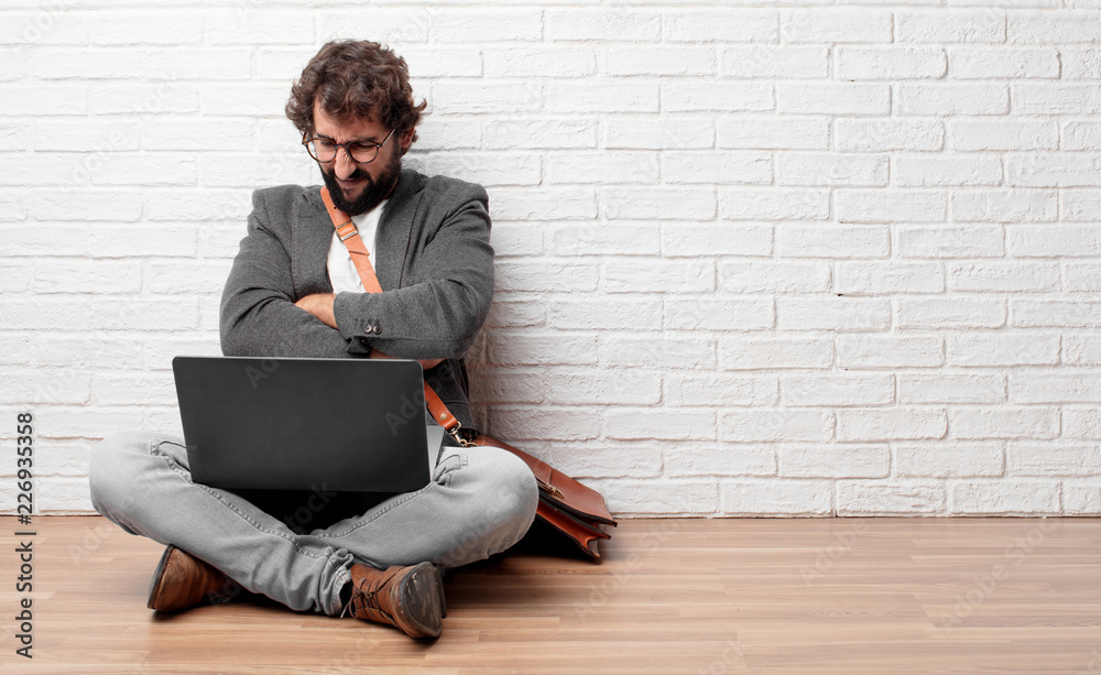 young man sitting on the floor looking angry, unhappy and frustrated ...