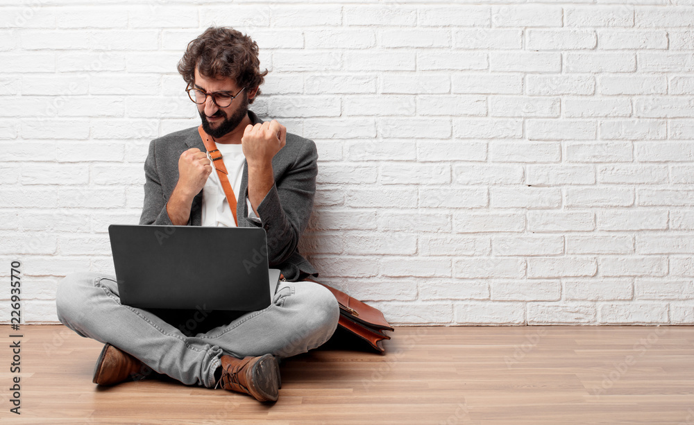 young man sitting on the floor with an angry, aggressive and menacing ...
