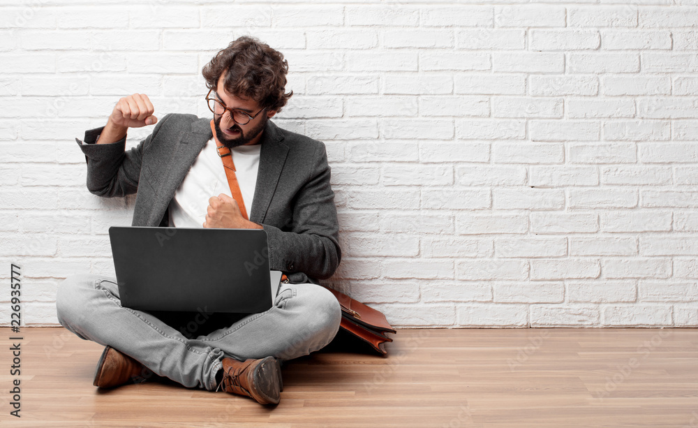 young man sitting on the floor with an angry, aggressive and menacing ...