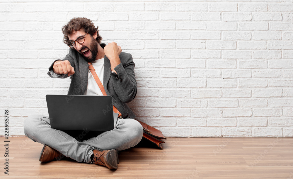 young man sitting on the floor with an angry, aggressive and menacing ...