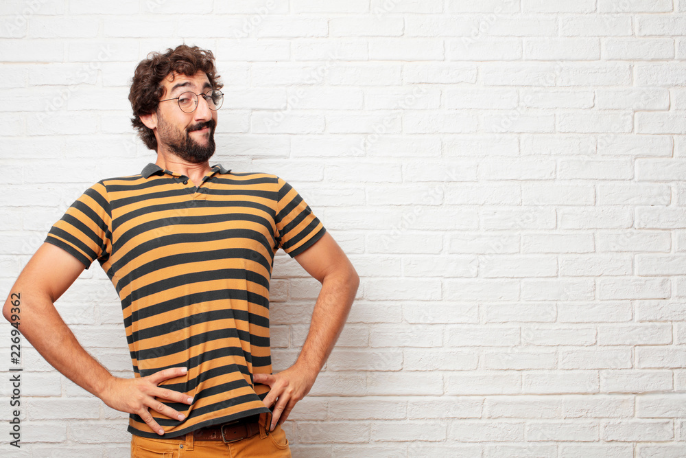 young dumb man smiling proudly and confidently with arms hands on hips ...