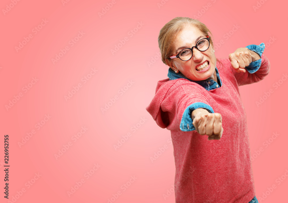 Beautiful senior woman with an angry, aggressive and menacing pose ...