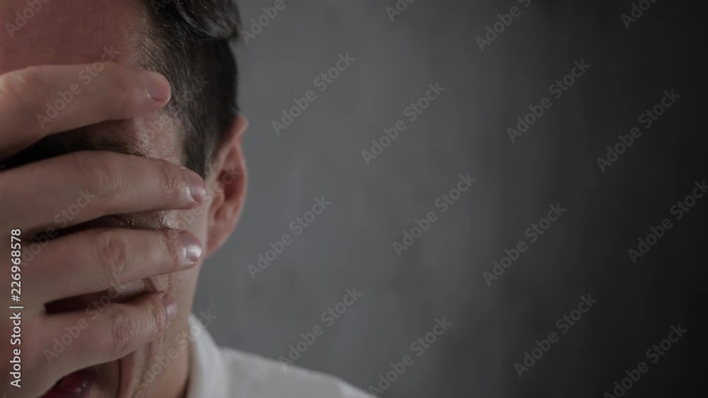 Half face of Young man in despair crying covering his face with his ...