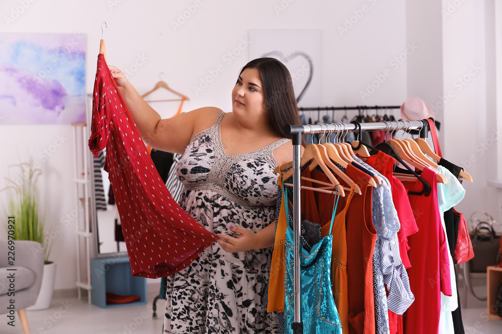 Overweight woman choosing clothes in shop Stock Photo | Adobe Stock