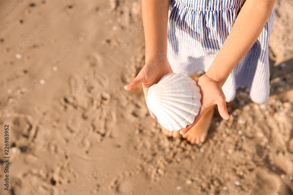 Cute little girl with sea shell on beach, closeup Stock Photo | Adobe Stock