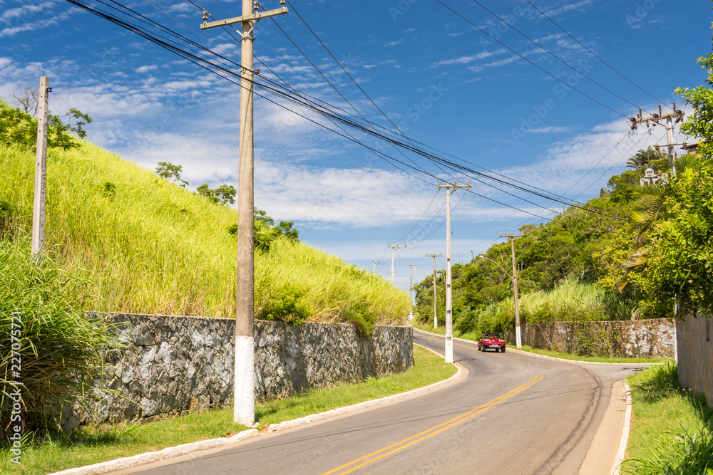 Pavement road with a red buggy car, in Buzios, Brazil, connecting the ...