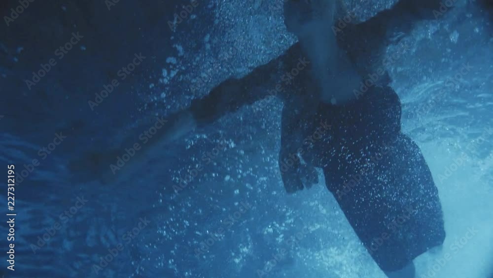 Amazing woman in a black dress swimming in the night time on the pool ...