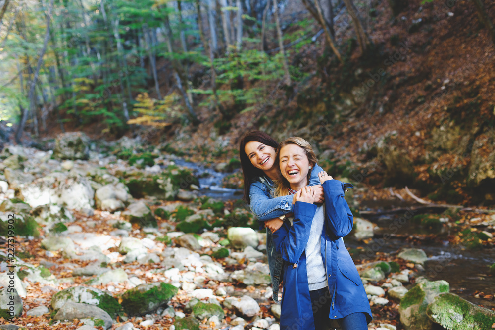 Two young girls friends walking and having fun in the autumn forest ...