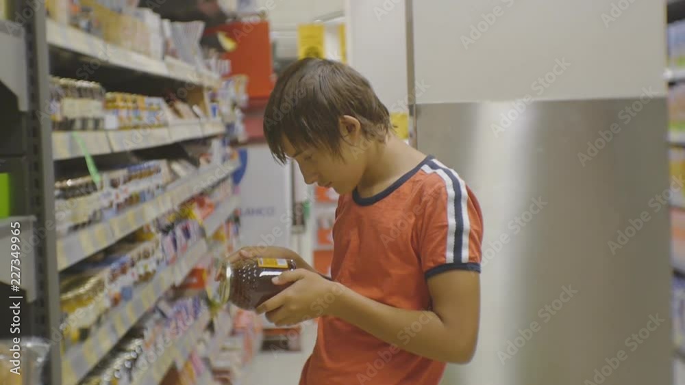 Teenager in supermarket. Caucasian teen boy in red t-shirt choosing and ...