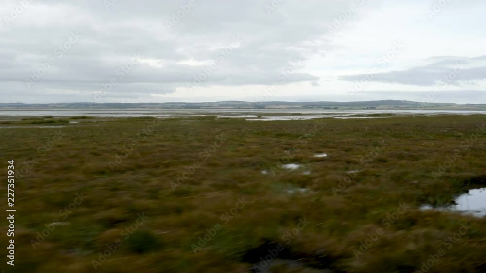 POV-Drive Plate-Shoreline grassy marsh land along a tidal flat that is ...