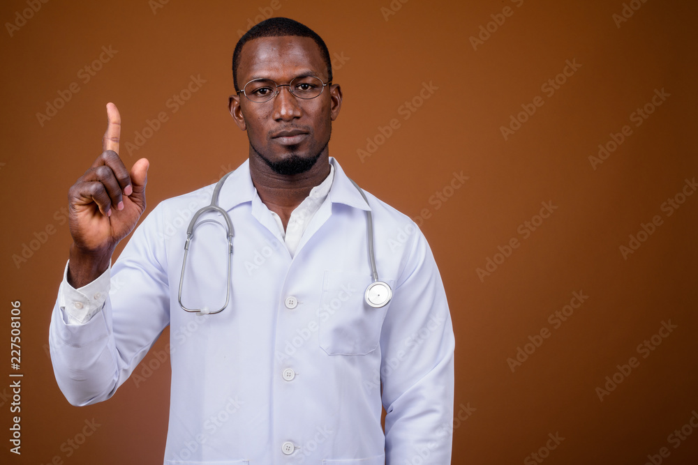 Handsome African man doctor wearing eyeglasses against brown bac Stock ...
