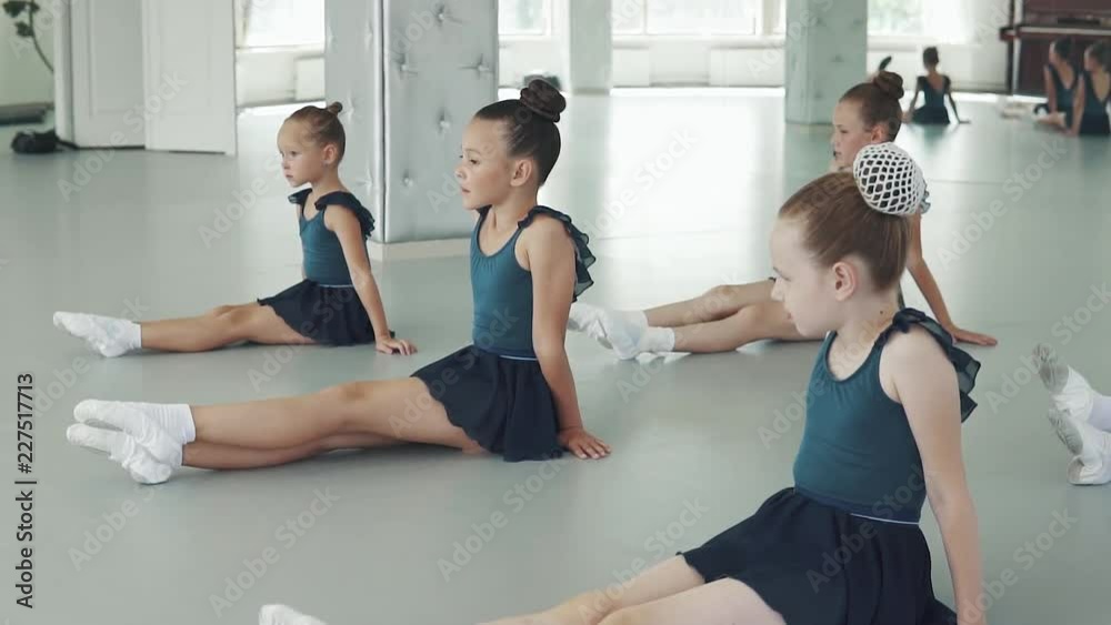 children in a dance lesson. little girls sit on the floor and repeat ...