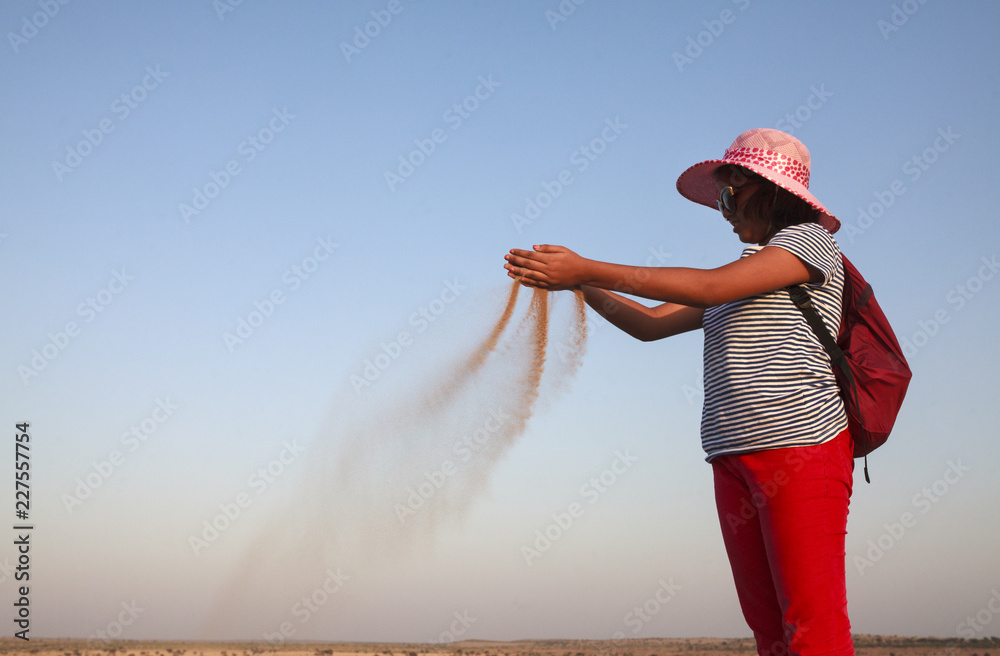 Teenage girl making fun with sand in Thar Desert Stock Photo | Adobe Stock