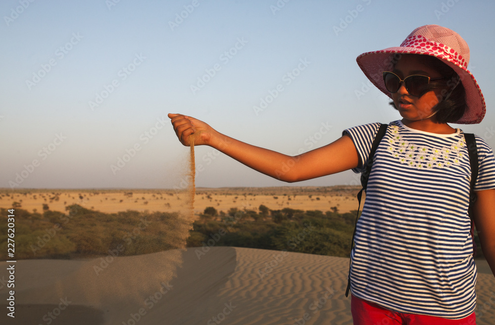 Teenage girl making fun with sand in Thar Desert Stock Photo | Adobe Stock