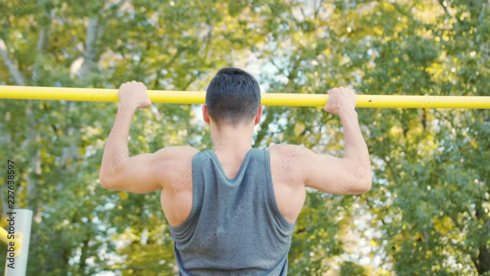 Young muscular man doing pull up exercise on horizontal bar. Slim ...
