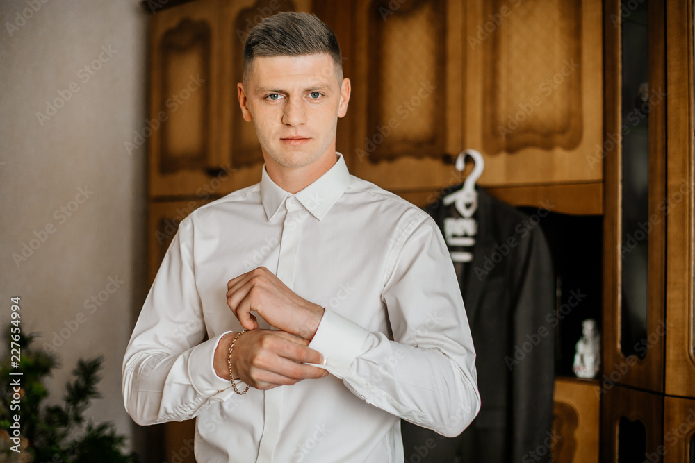 stylish groomsmen helping happy groom getting ready in the morning for ...