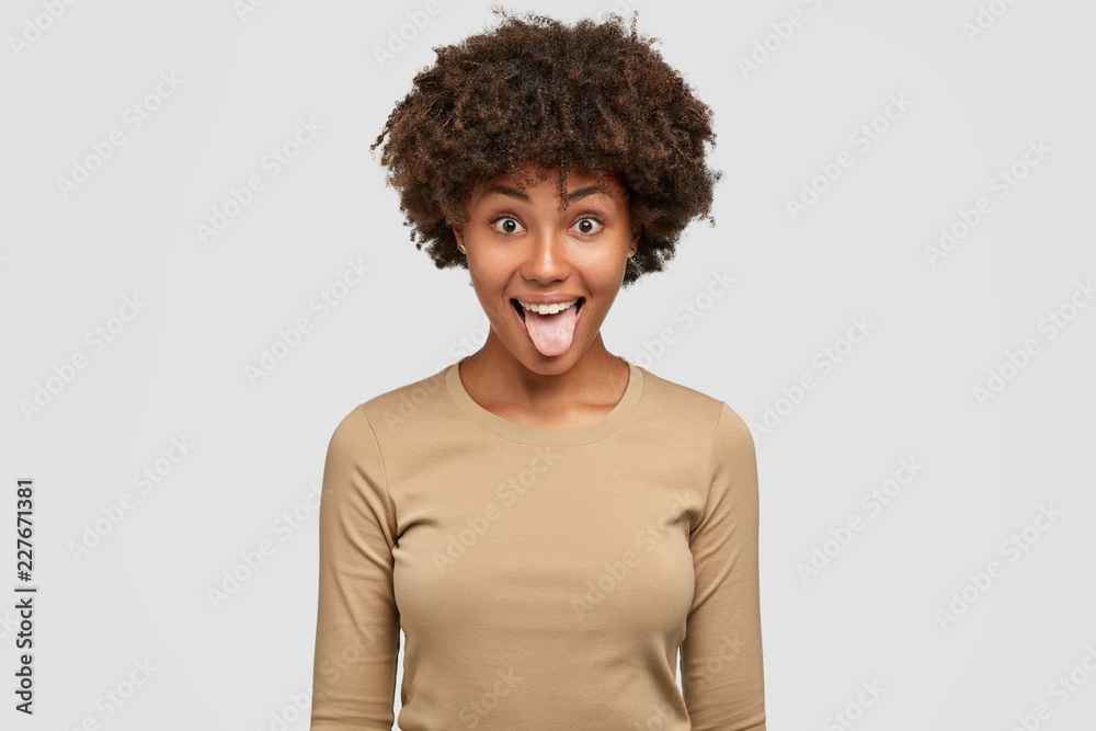 Studio shot of funny black woman shows tongue, has playful expression ...