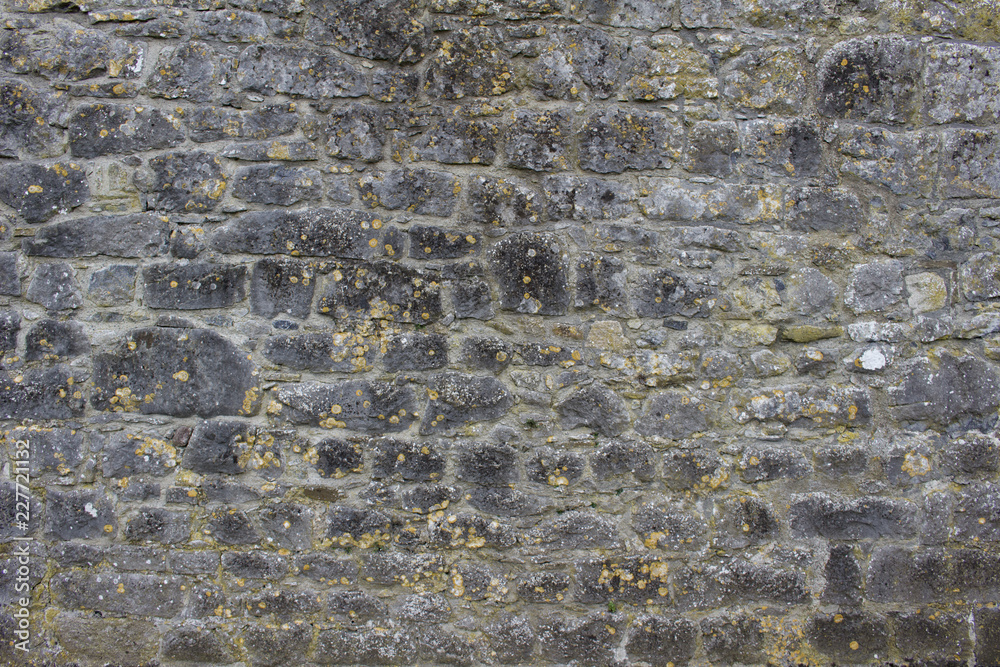 Medieval gray color stone wall background with aged appearance and ...
