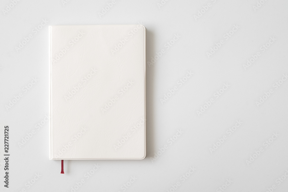 Top view of closed blank white leather cover notebook on white desk ...