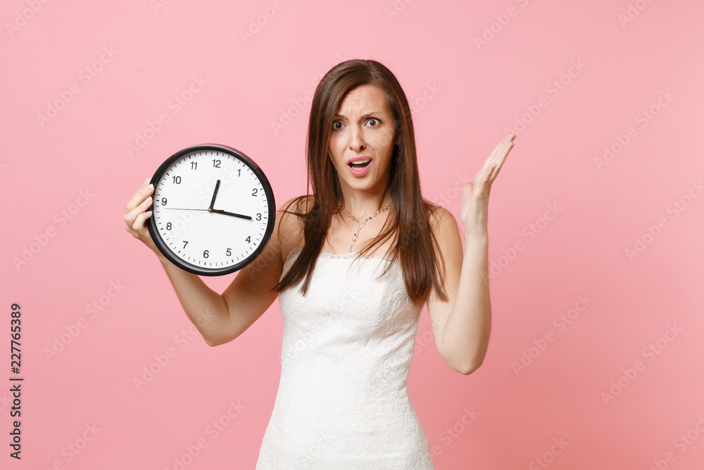 Irritated bride woman in white wedding dress spreading hand hold round ...