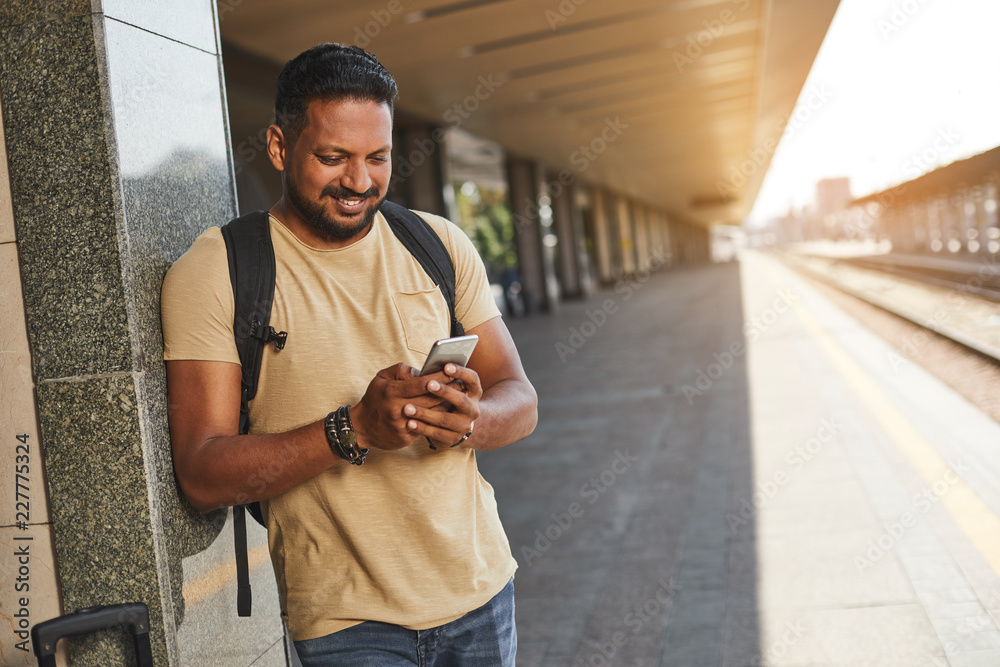 Positive handsome hindu man typing a message while using phone at the ...