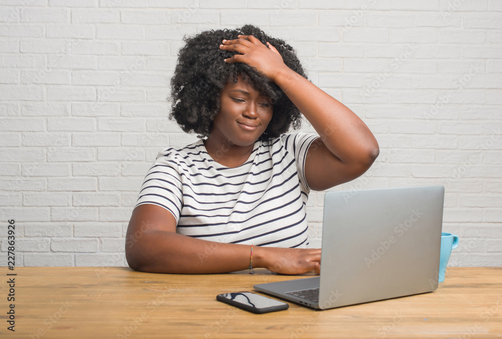 Young african american woman sitting on the table using computer laptop ...