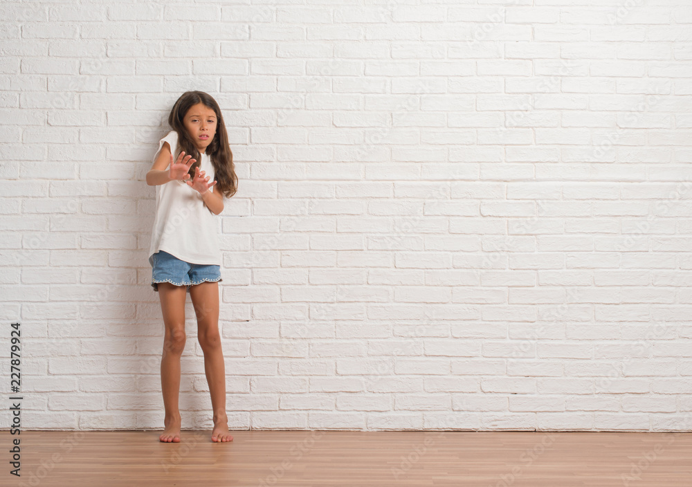 Young hispanic kid stading over white brick wall disgusted expression ...