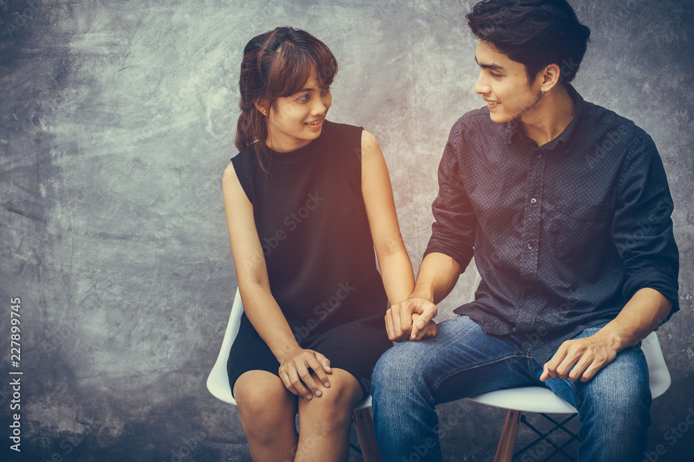 Young couples sitting on a chair inside the room which walls are made ...