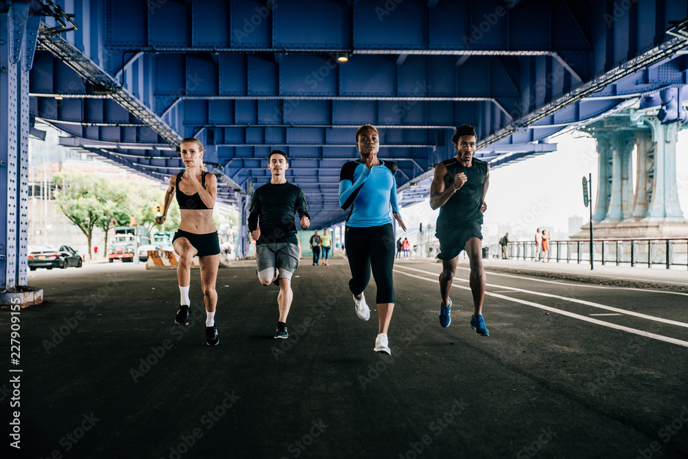 Group of urban runners running on the street in New york city ...