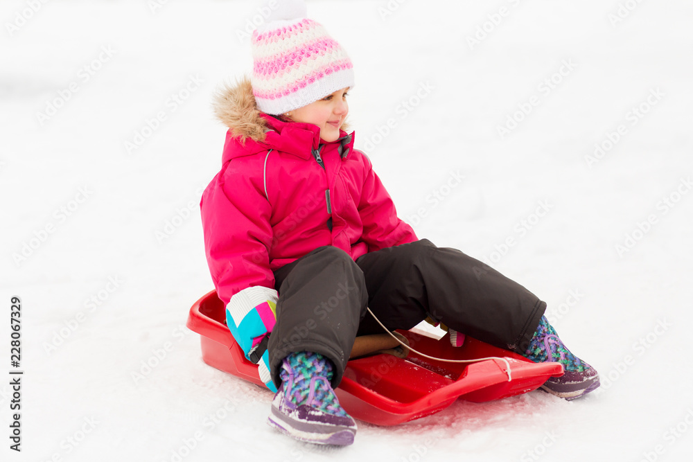 childhood, sledging and season concept - happy little girl sitting in ...