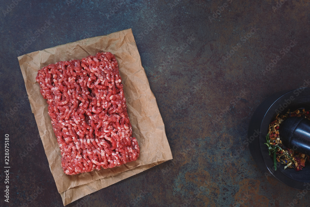 Fresh raw grass fed angus ground beef on parchment paper, concrete ...