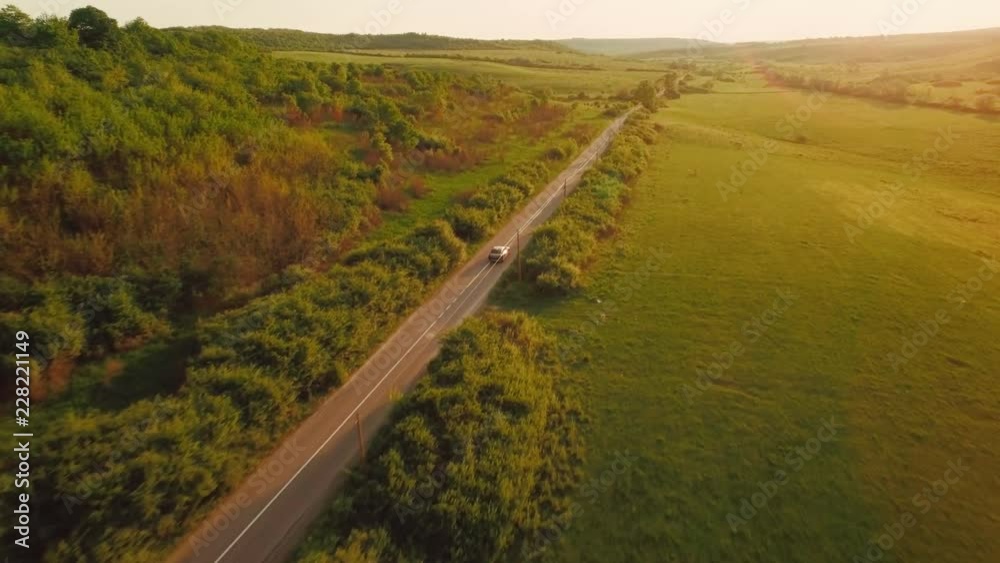 Aerial view of a car passing through green fields and forest Stock ...
